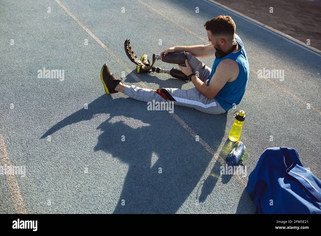 Caucasian male athlete fixing his prosthetic leg while sitting on ...