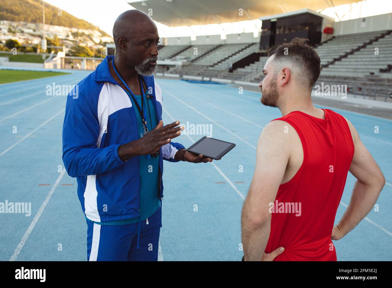 African american male coach instructing caucasian male athlete with ...