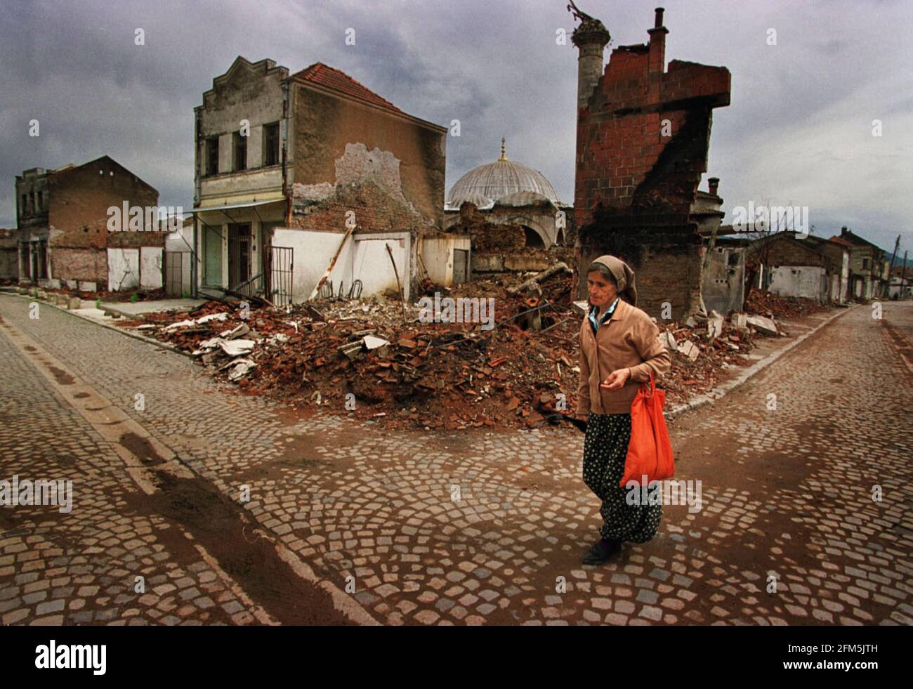 Woman walks through the ruins of jakovica old June 1999 town Stock ...