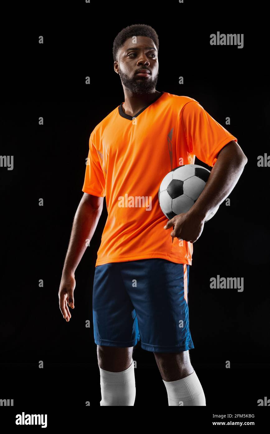 Portrait of young African soccer player posing isolated on black ...