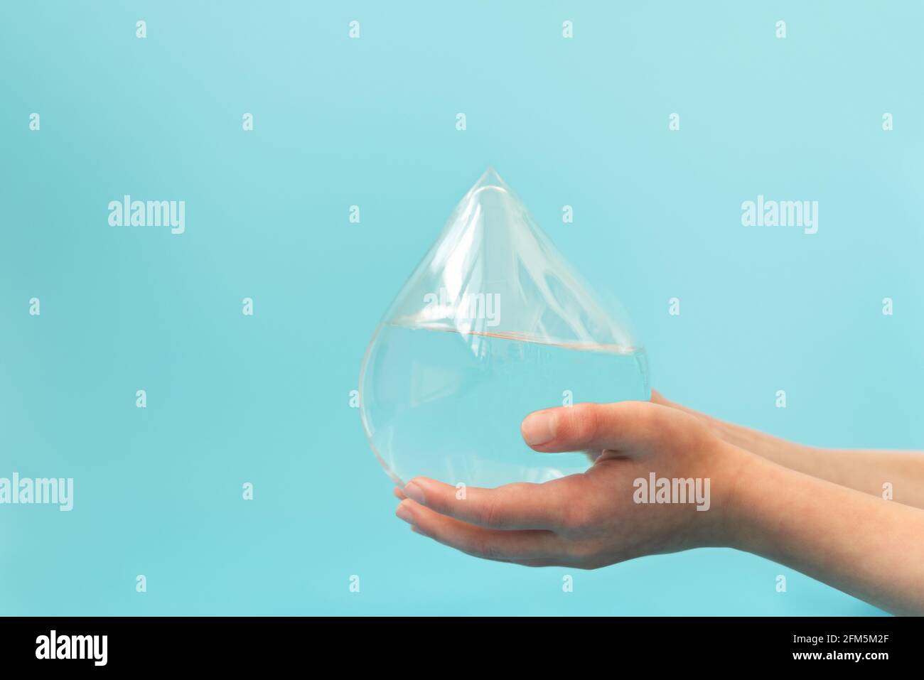 Hands holding glass water drop on blue background. World environment ...