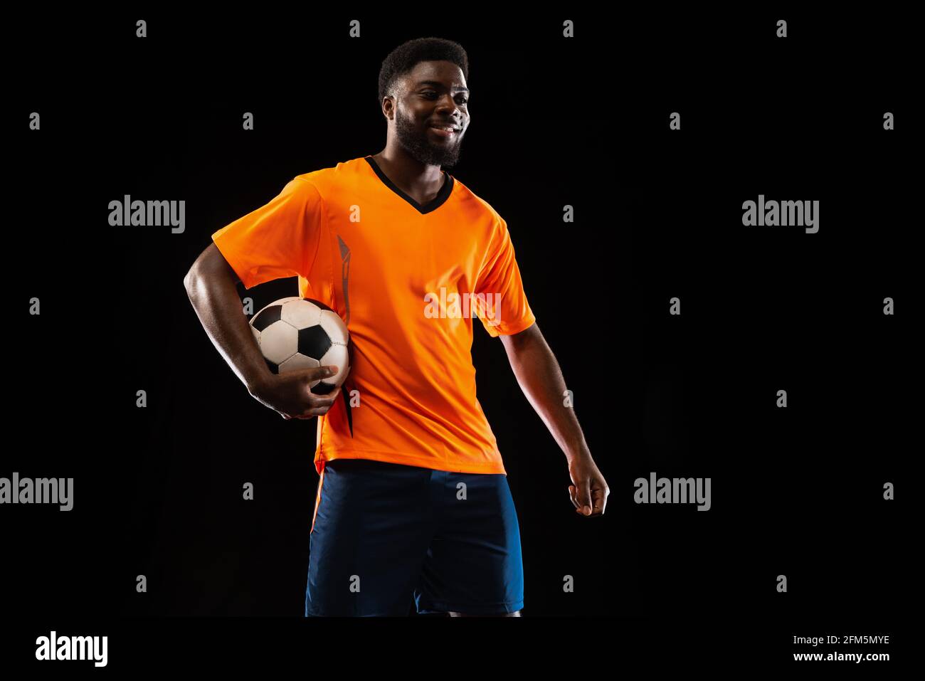 Portrait of young African soccer player posing isolated on black ...