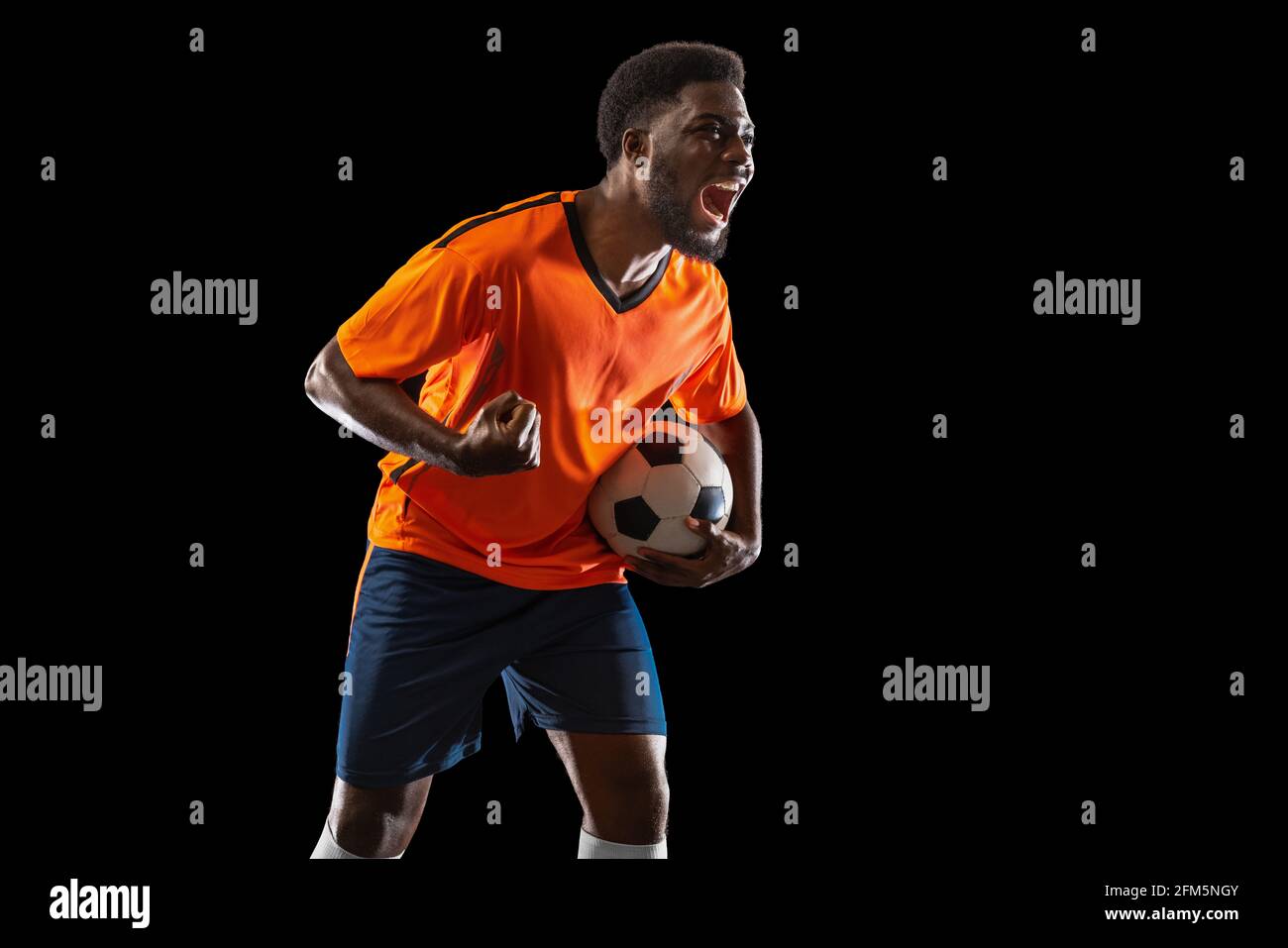 Portrait of young African soccer player posing isolated on black ...