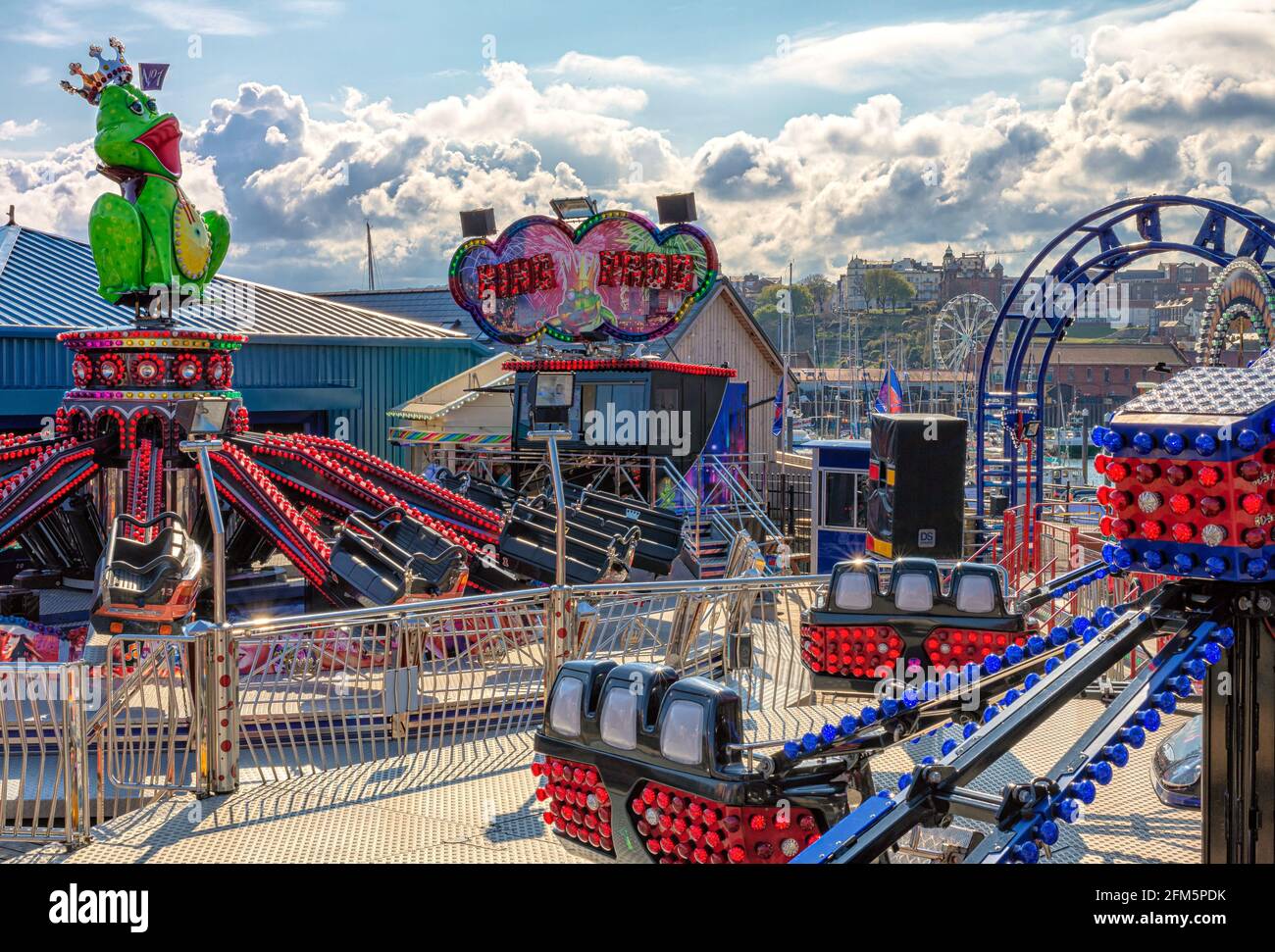 Colourful rides with lights in a fairground at the seaside.The town is ...