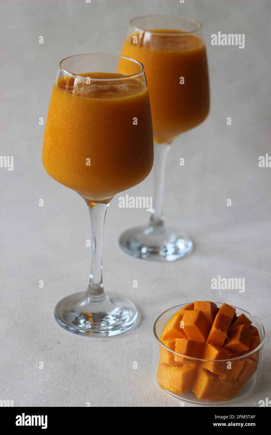 Two glasses of mango juice with nicely sliced mango kept beside. Shot ...