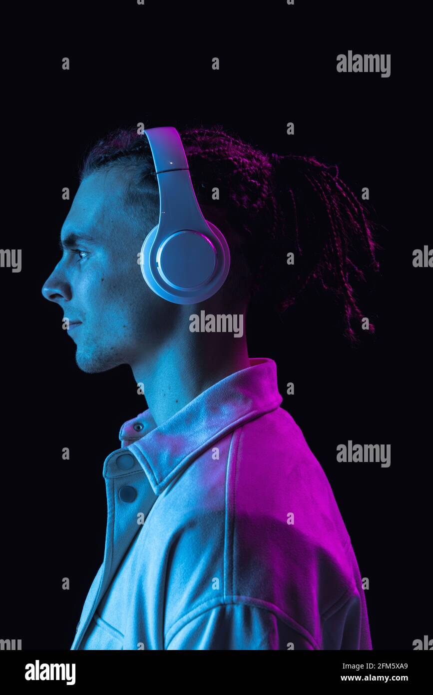 Close-up Caucasian young man isolated on dark studio background in neon ...