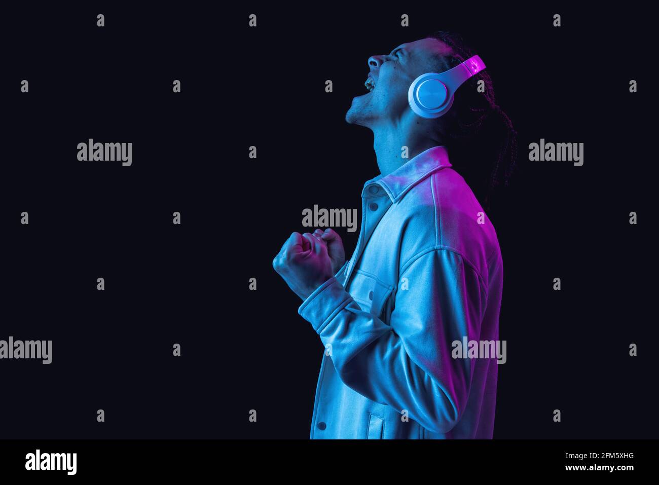 One Caucasian young man isolated on dark studio background in neon ...