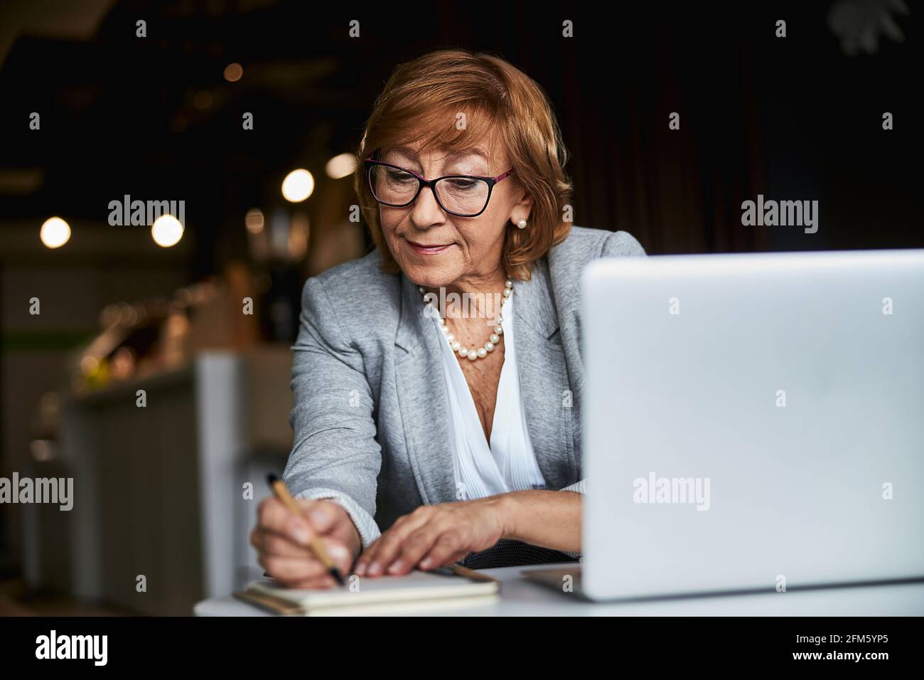 Beautiful female person making notes during online conference Stock ...