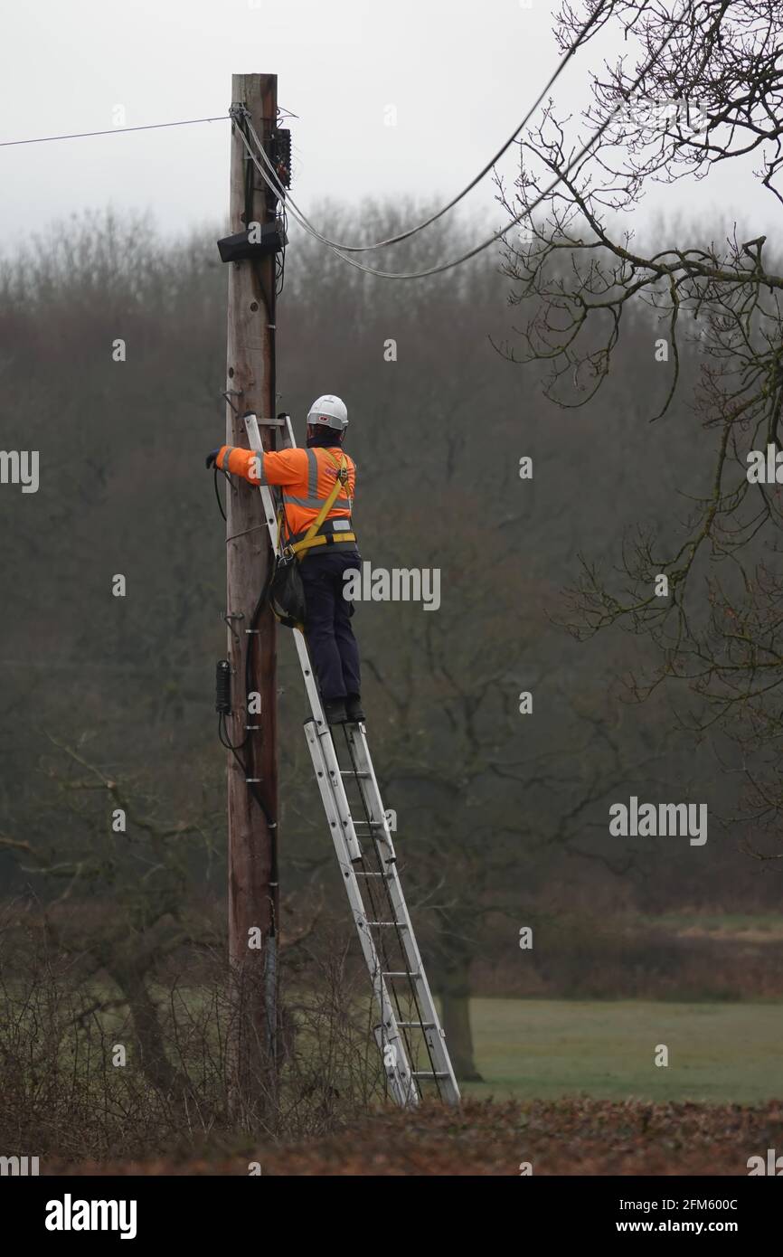 British Telecom Openreach engineer working at height at the top of a ...