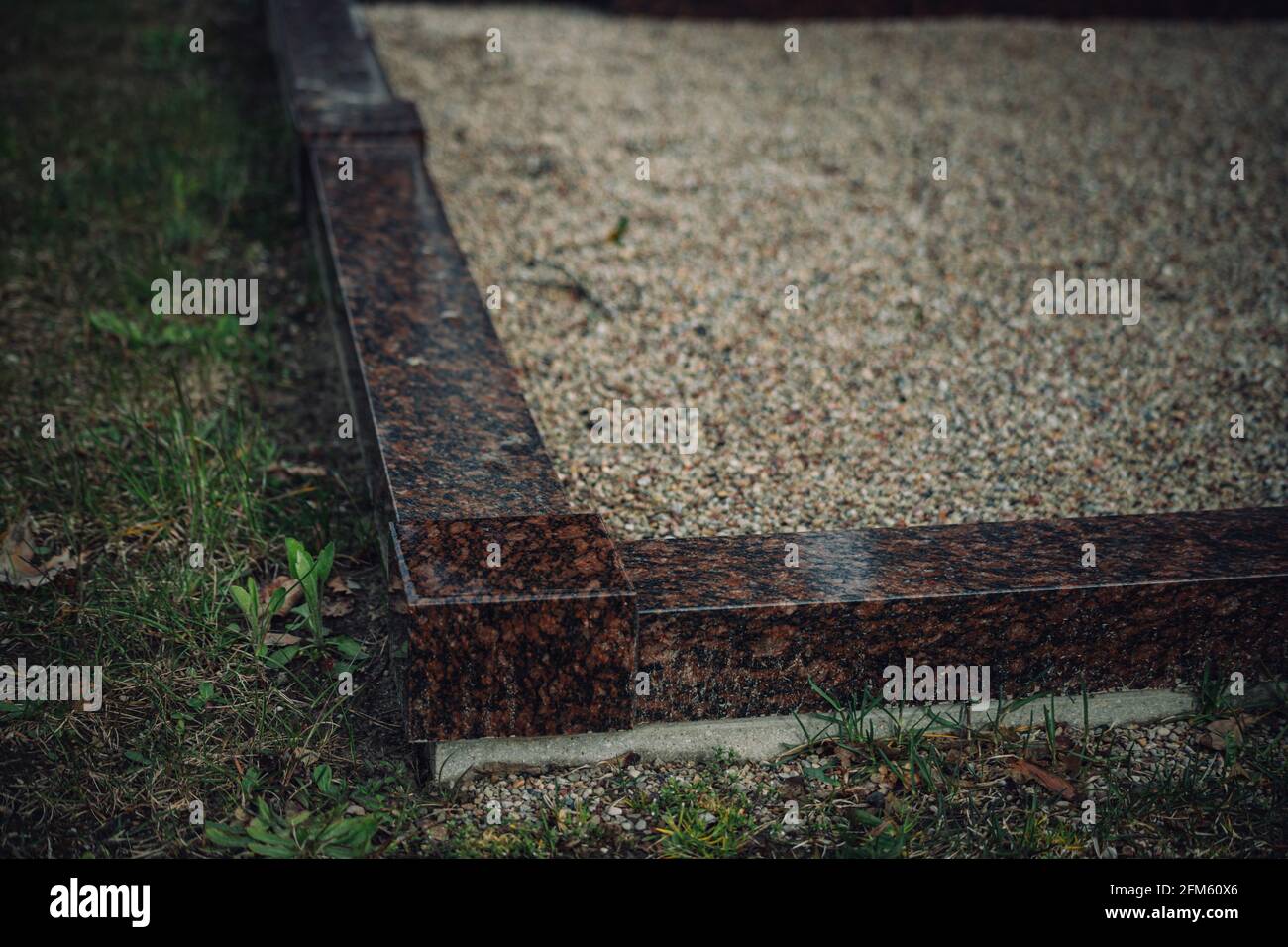 border of grave site made of polished granite. Small pebbles inside ...