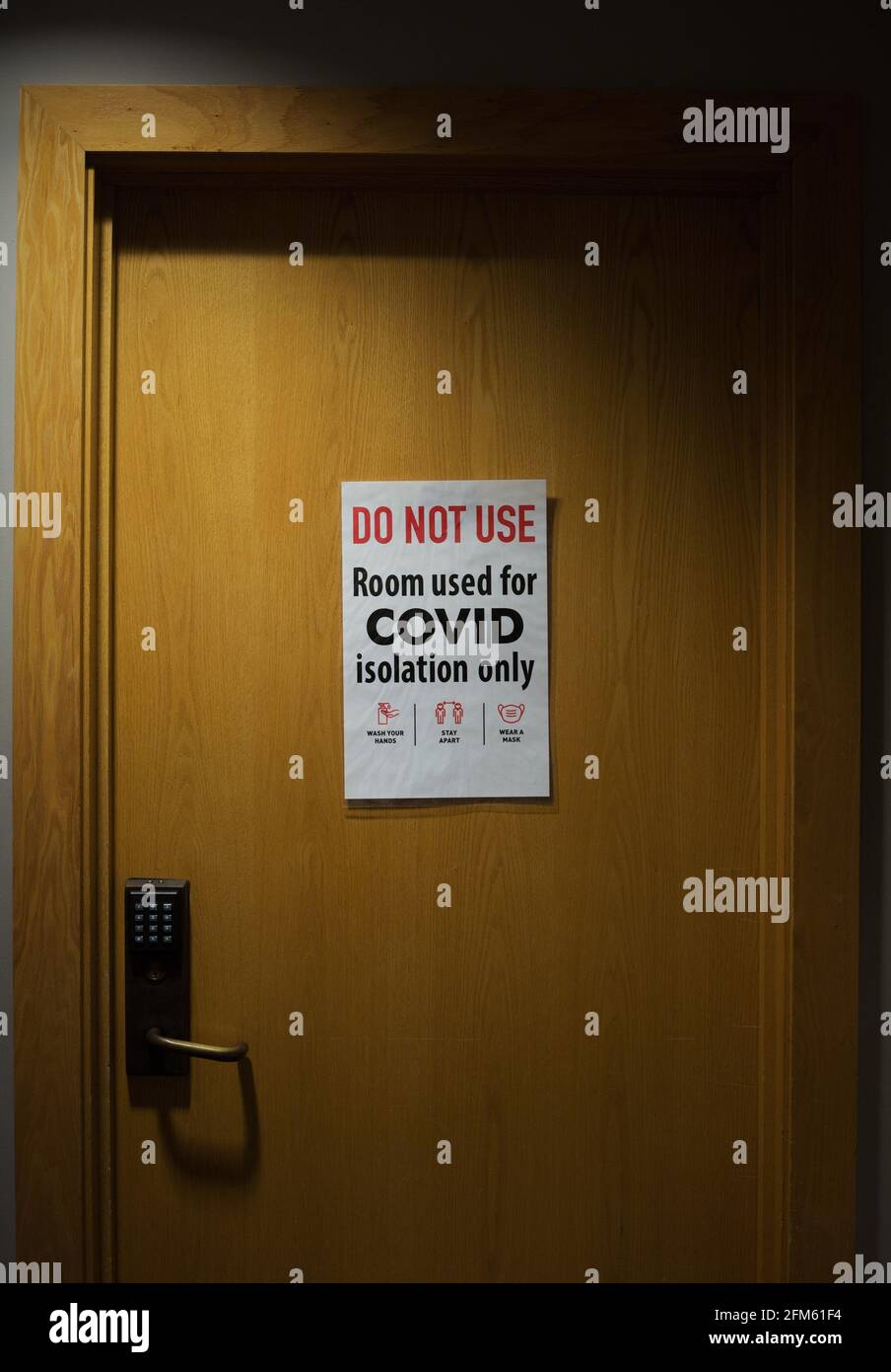 A door in shadow, with sign that reads "Do not use, room used for covid ...