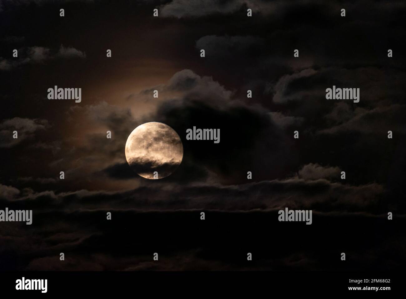 Spooky night sky with full moon partially hidden by clouds Stock Photo ...
