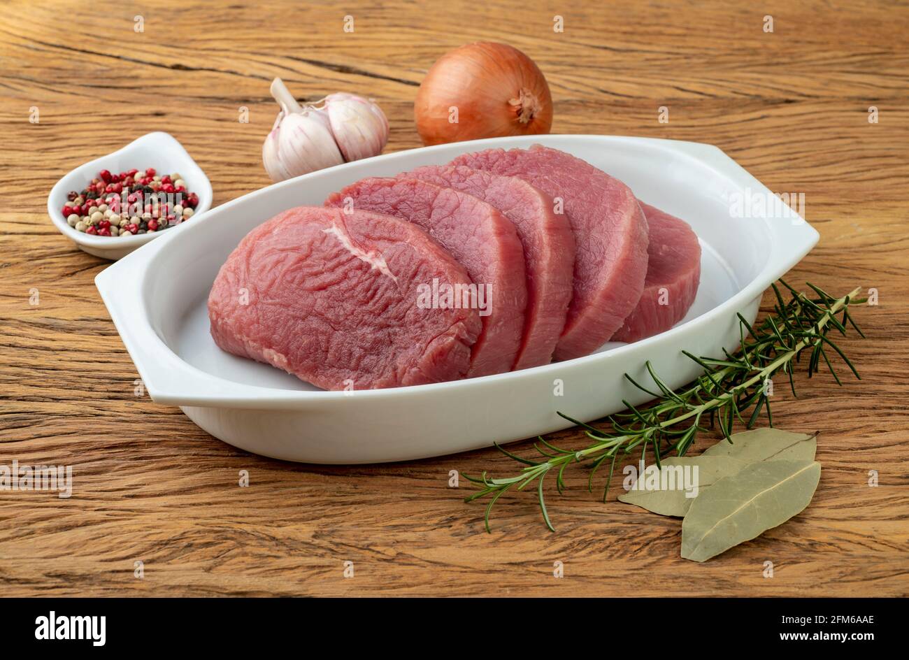 Cut raw eye round meat over white plate with seasonings Stock Photo - Alamy