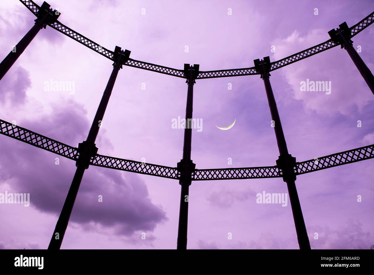 Purple cloudy sky with moon and gas holder frame Stock Photo - Alamy