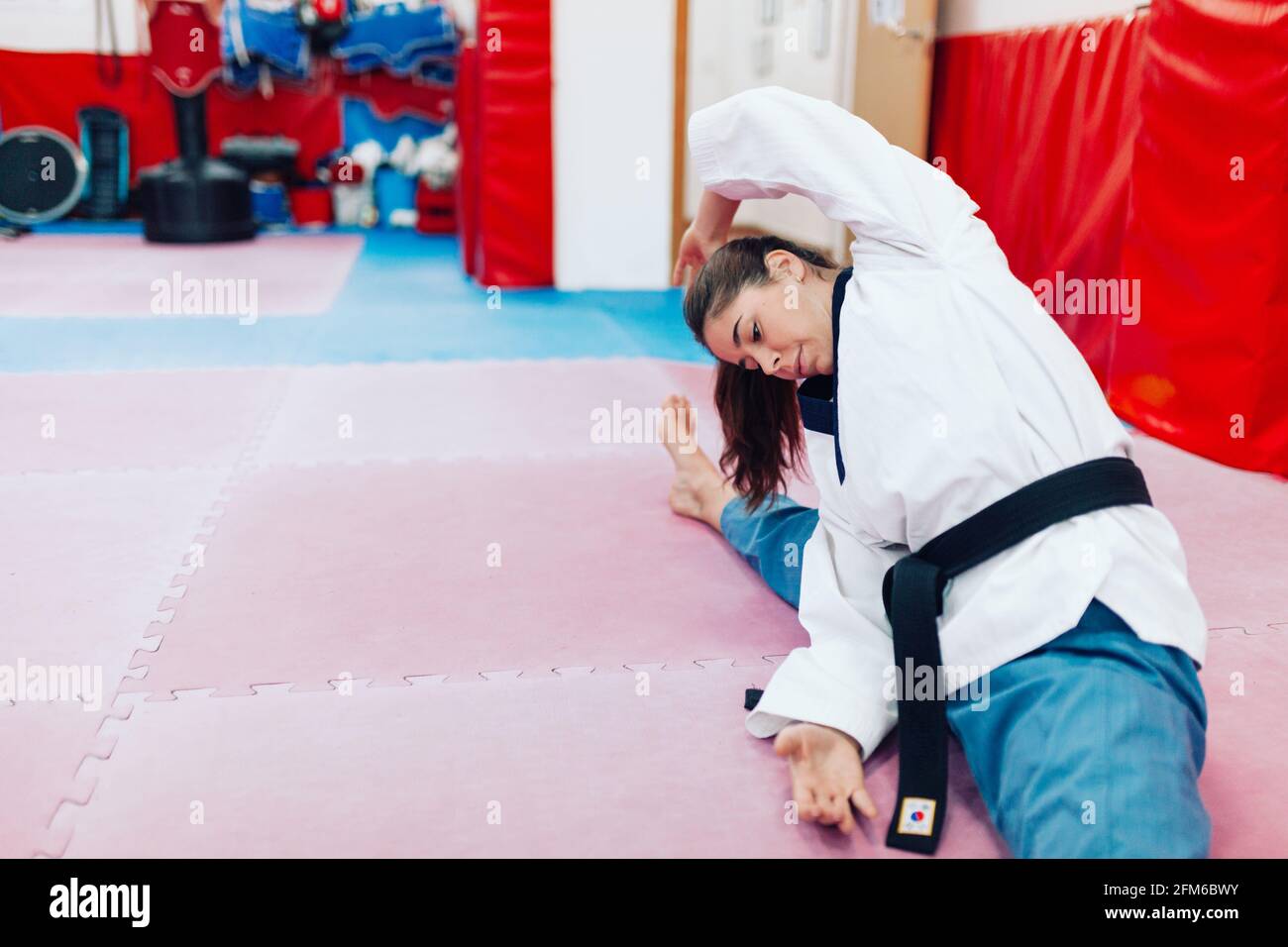 Young woman stretching in a dojo wearing taekwondo dobok Stock Photo ...