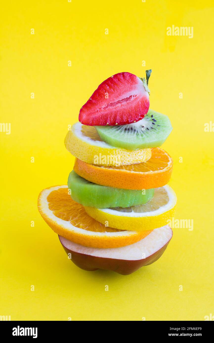 Pyramid of chopped fruit in balance on the yellow background. Close-up ...