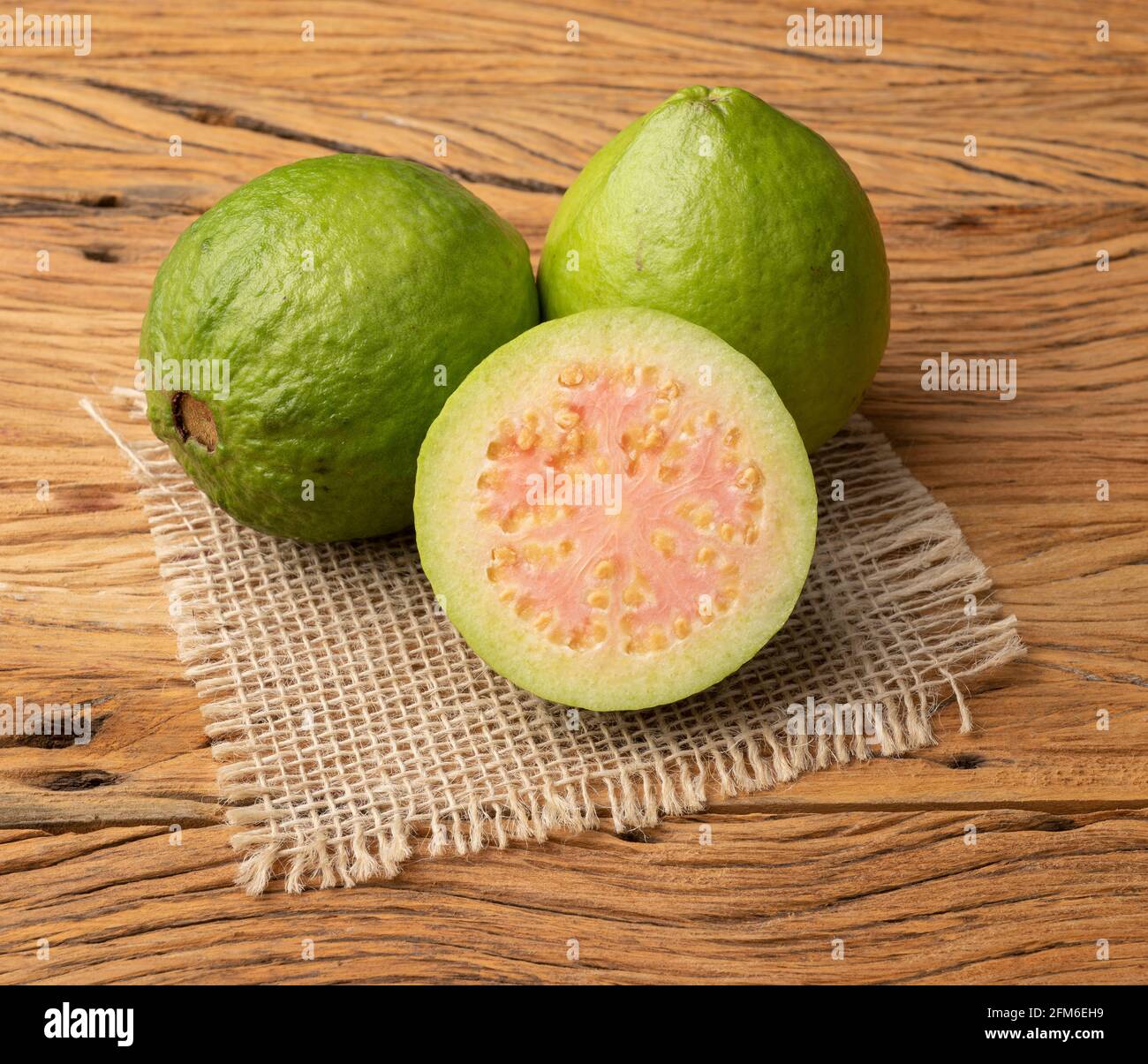 Red guavas with half fruit over wooden table Stock Photo - Alamy