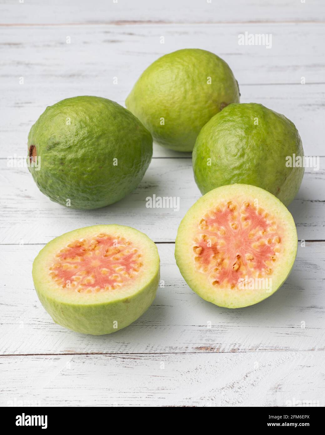 Red guavas and half fruits over wooden table Stock Photo - Alamy