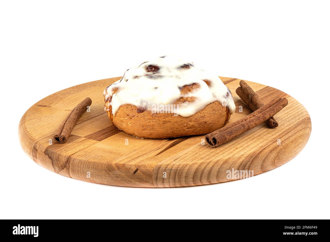 Cinnabon bun covered with icing sugar and cinnamon sticks on a cutting ...