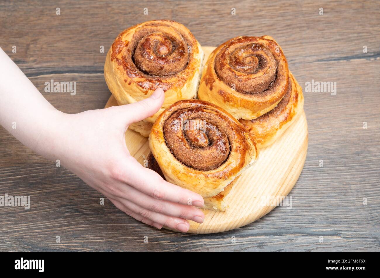 A woman's hand takes a freshly baked cinnabon bun. Homemade buns Stock ...