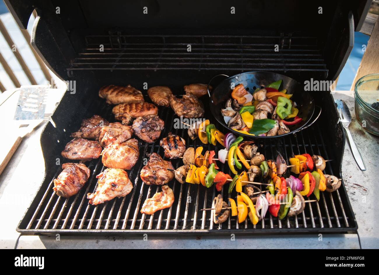 High angle of vegetable skewers and chicken on the grill of a gas bbq ...