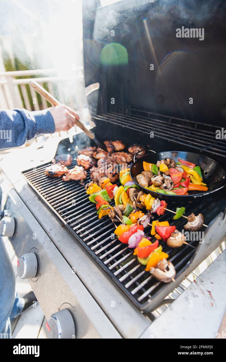 Hand grilling chicken and vegetables outdoors on a gas bbq grill Stock ...