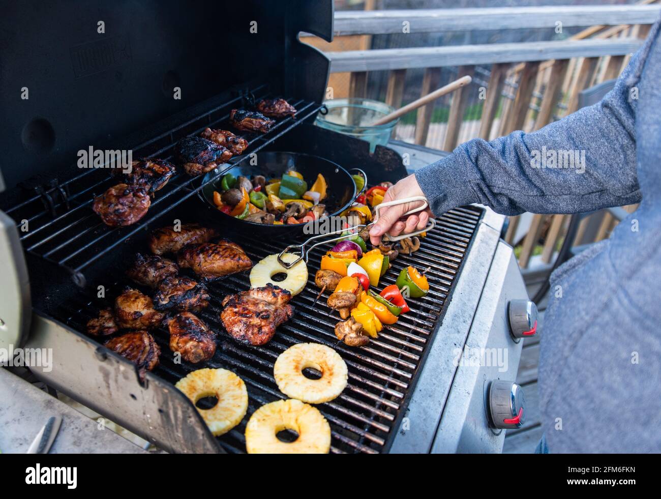 Man grilling chicken, vegetables and pineapple on a gas bbq grill Stock ...
