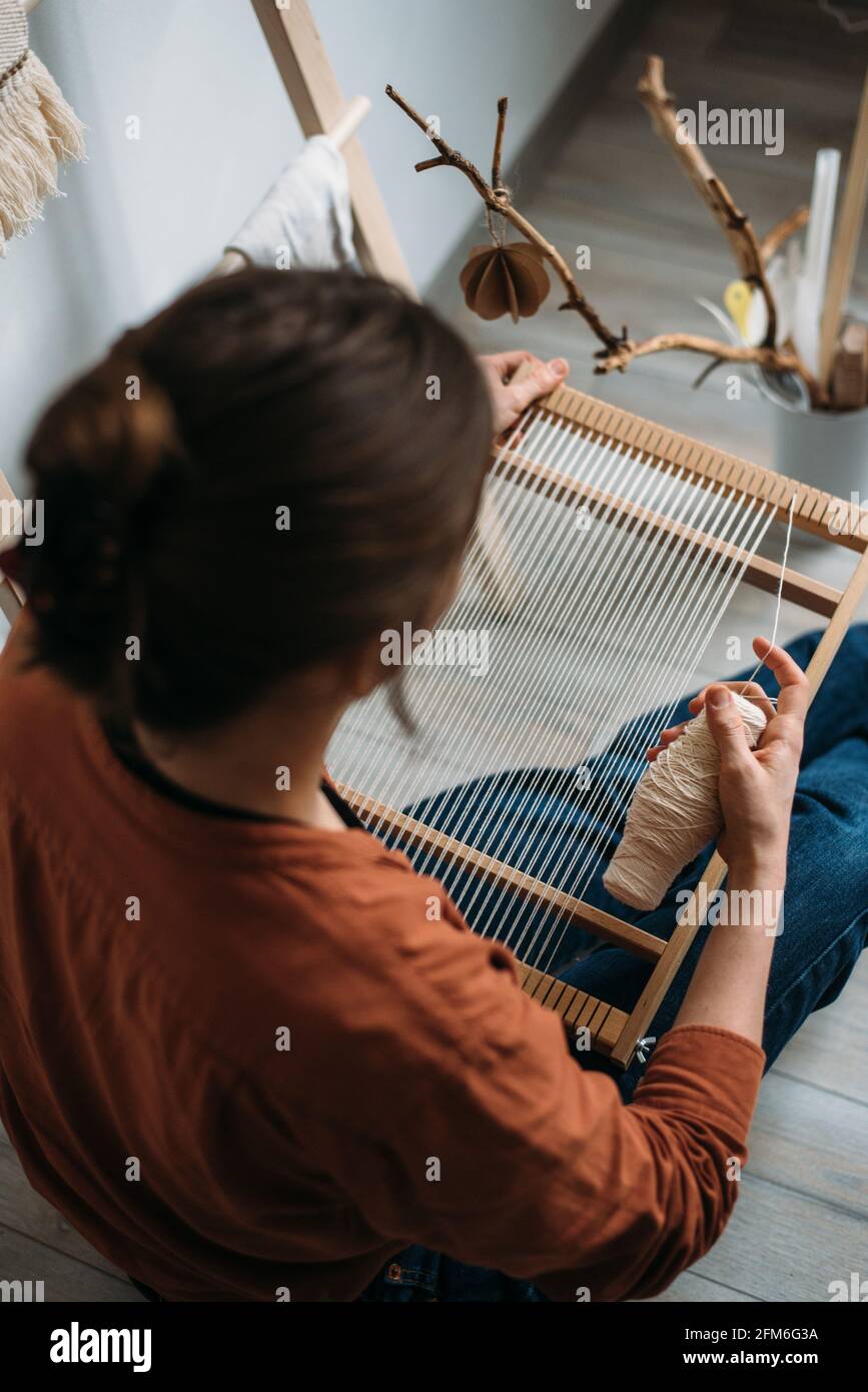 Back view of young woman preparing frame for wool weaving Stock Photo ...