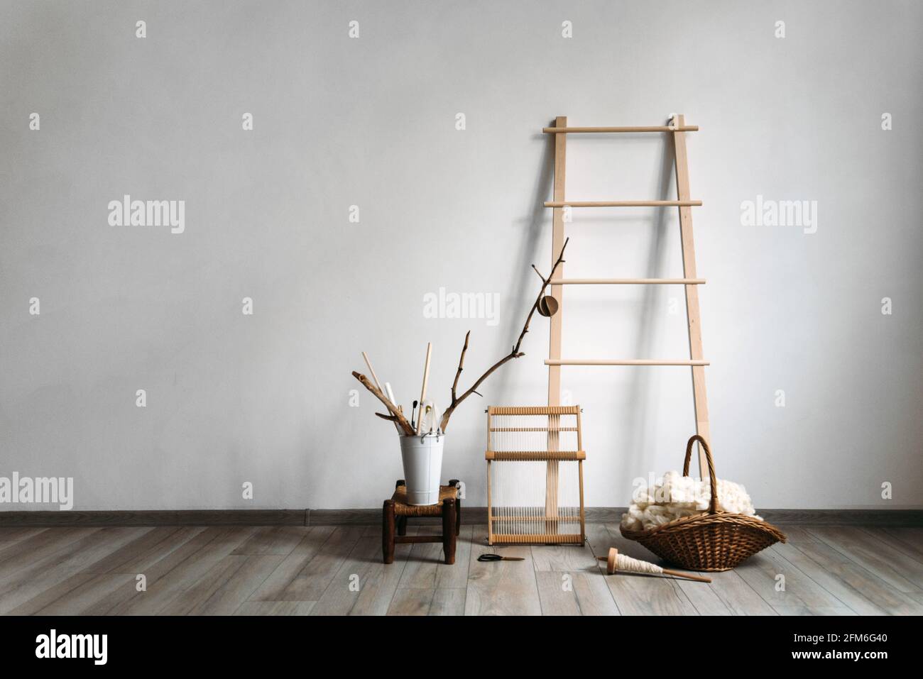 Still life with wool in basket, art instruments, frame, and weaved rug ...