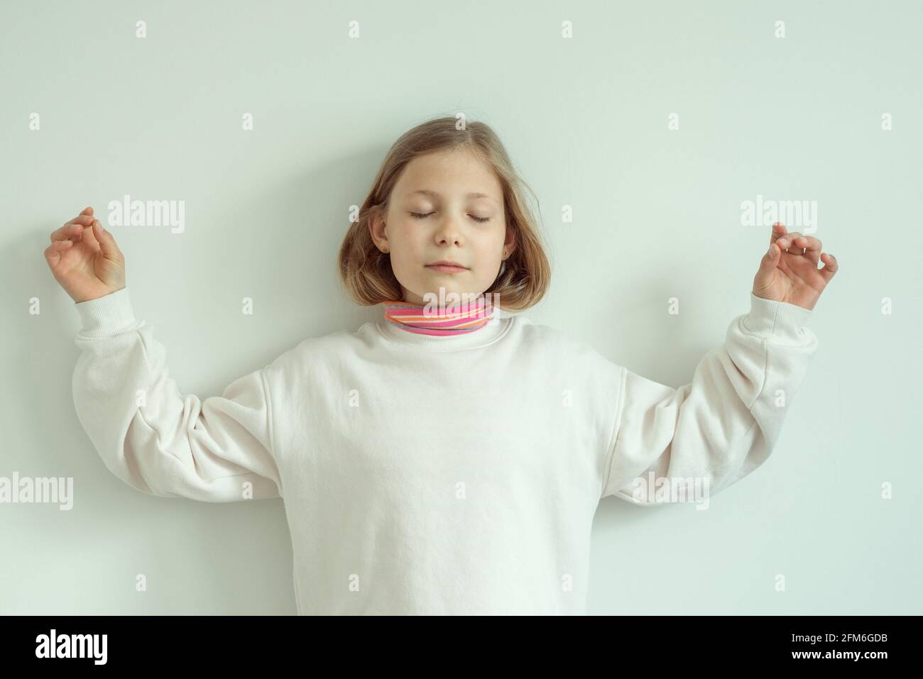 Portrait of pretty teen girl standing in yoga calm posture with closed ...