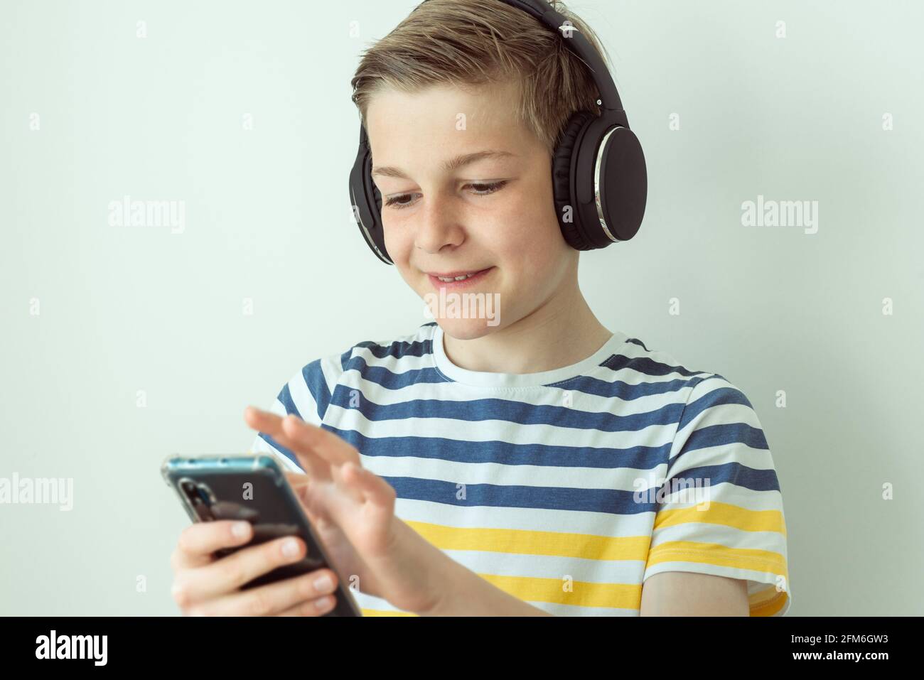 Handsome teen boy with headphones and cell phone on white background ...