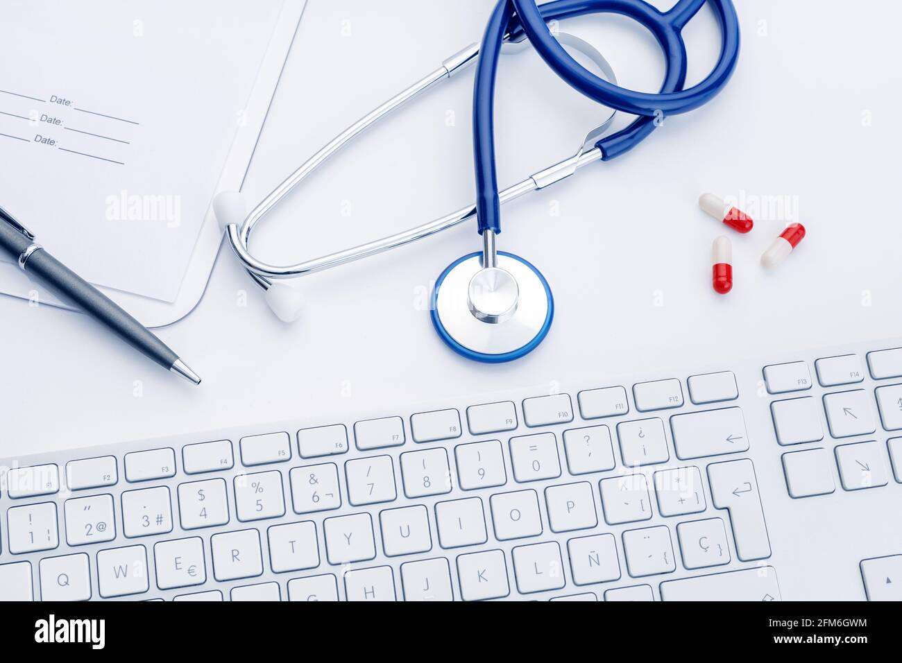Doctor desk with Stethoscope, computer keyboard and medicine pills on ...