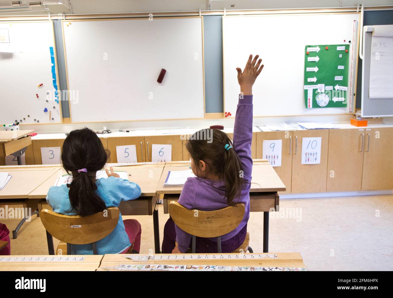 Teaching in a school. School child raising his hand during a lesson in ...