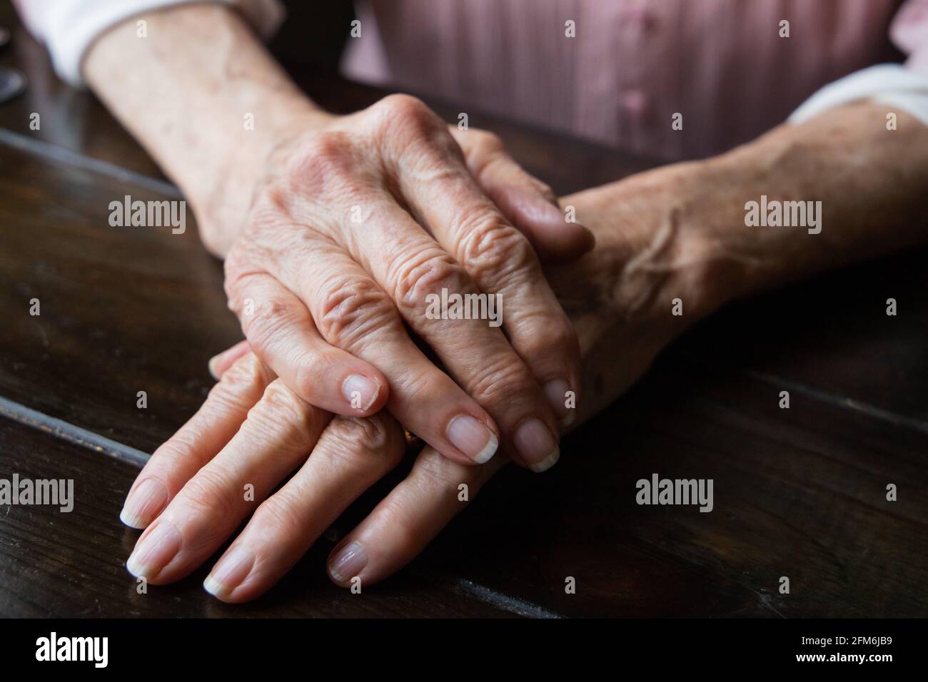 A pair of elderly woman grandmother's hands folded and laying on top of ...