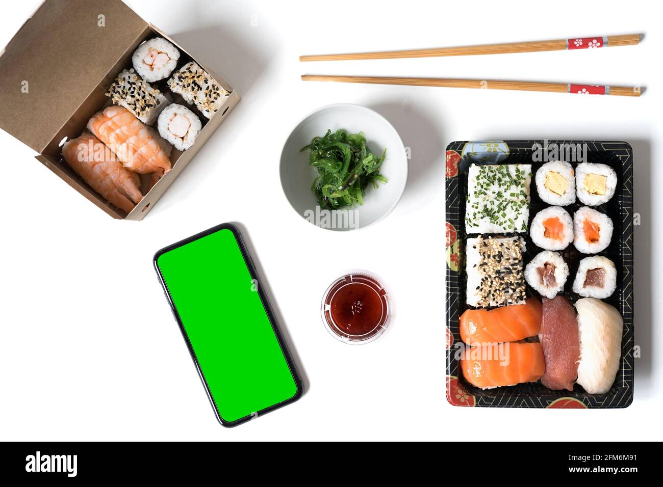Phone with green screen on a white table with sushi food in take-away ...