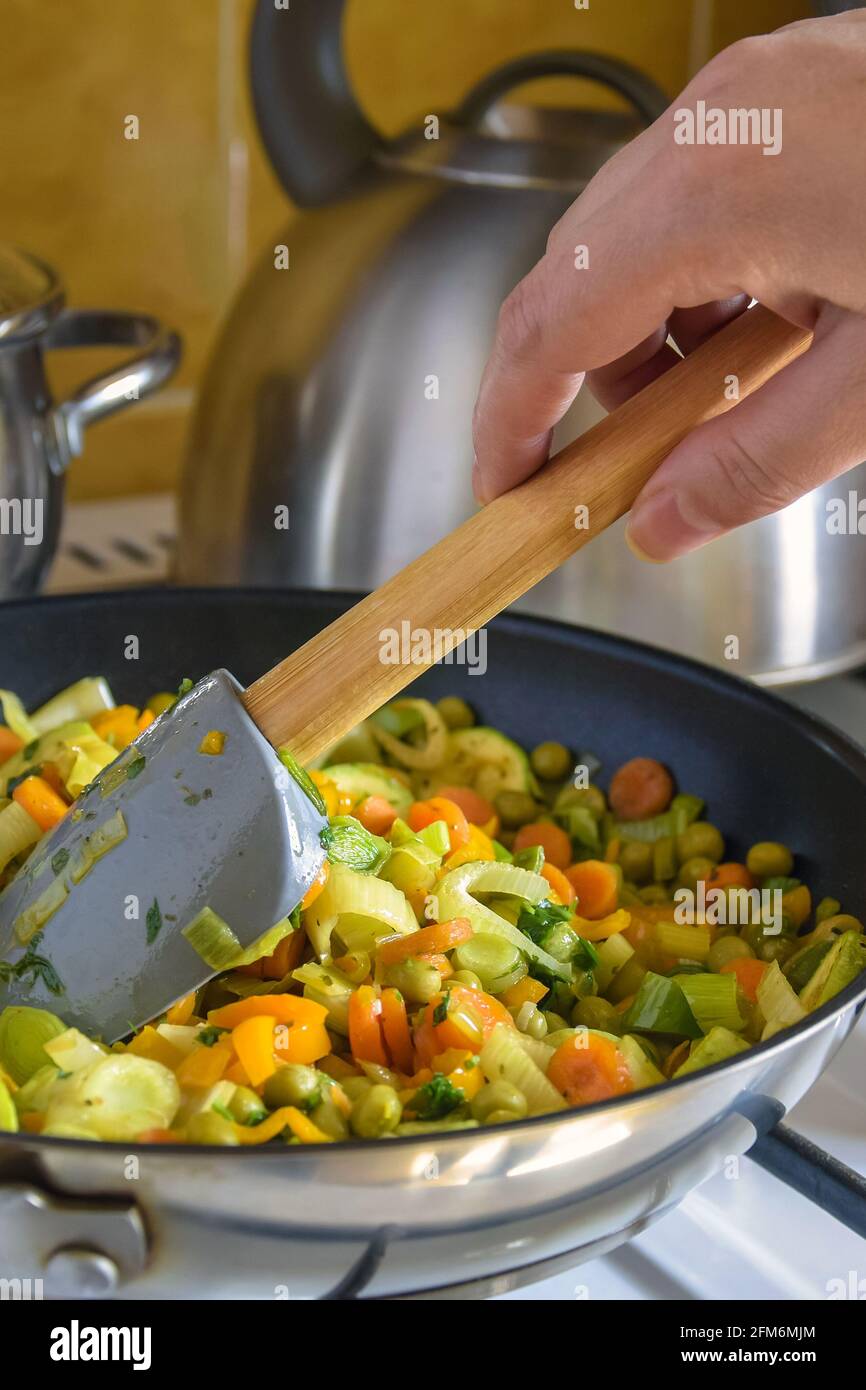Process of cooking saute at home. Woman's hand mixed stewed vegetables ...