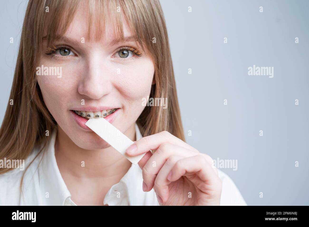 Young woman with metal braces on her teeth is chewing gum. The girl is ... Young woman with metal braces on her teeth is chewing gum. The girl is ...