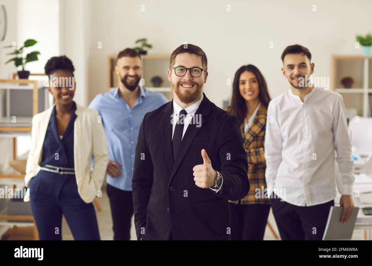 Confident team leader posing in office with diverse colleagues show ...