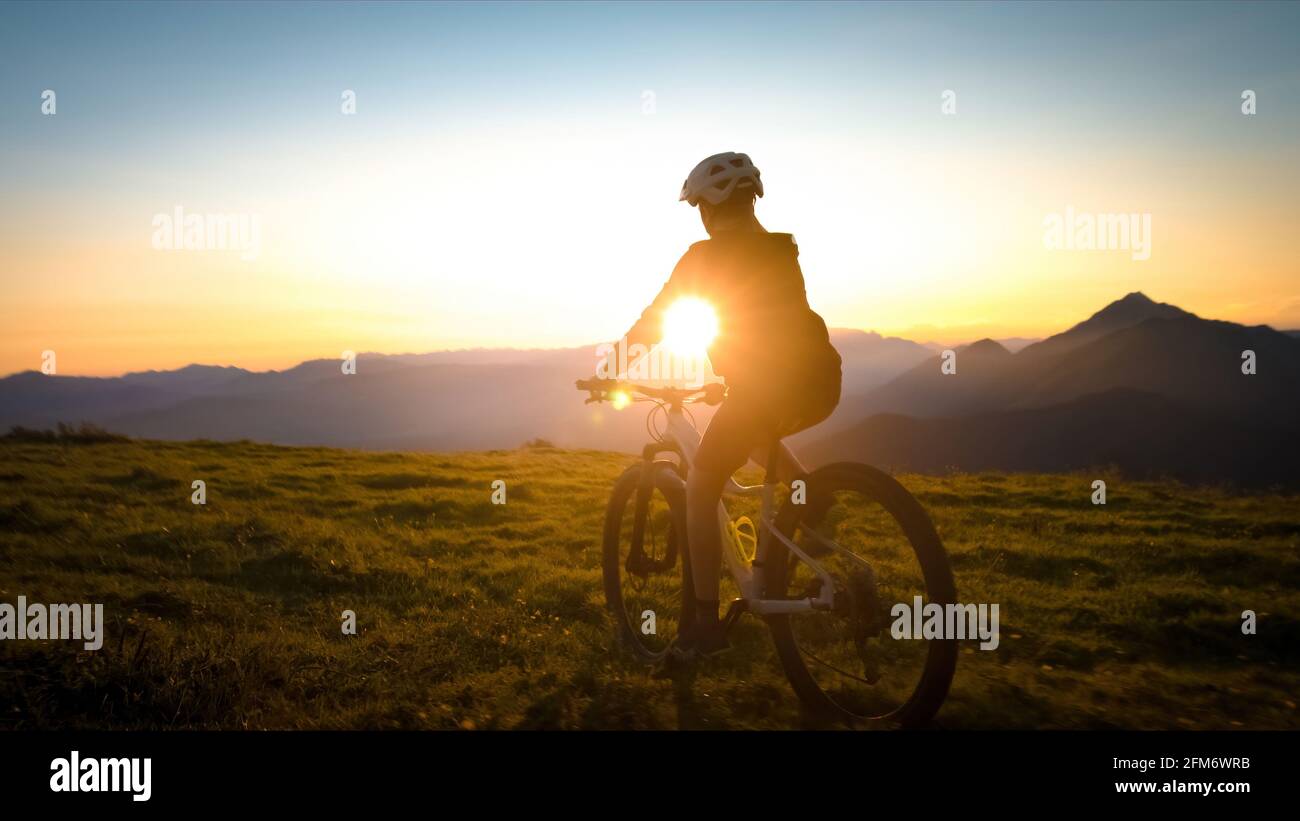 Girl child riding mountain bike into the sunset. Beautiful golden ...