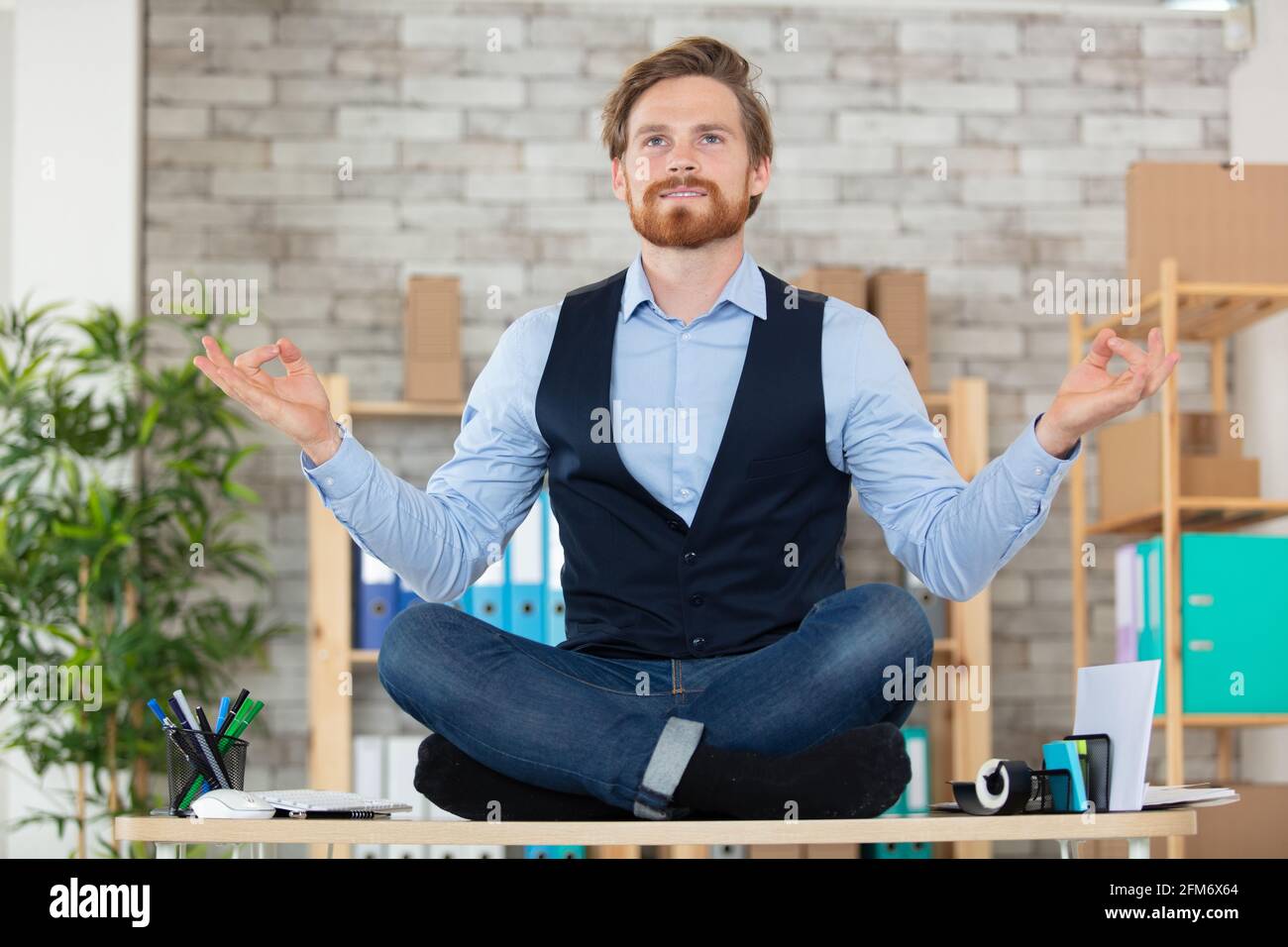 casual businessman meditating at his desk in the office Stock Photo - Alamy