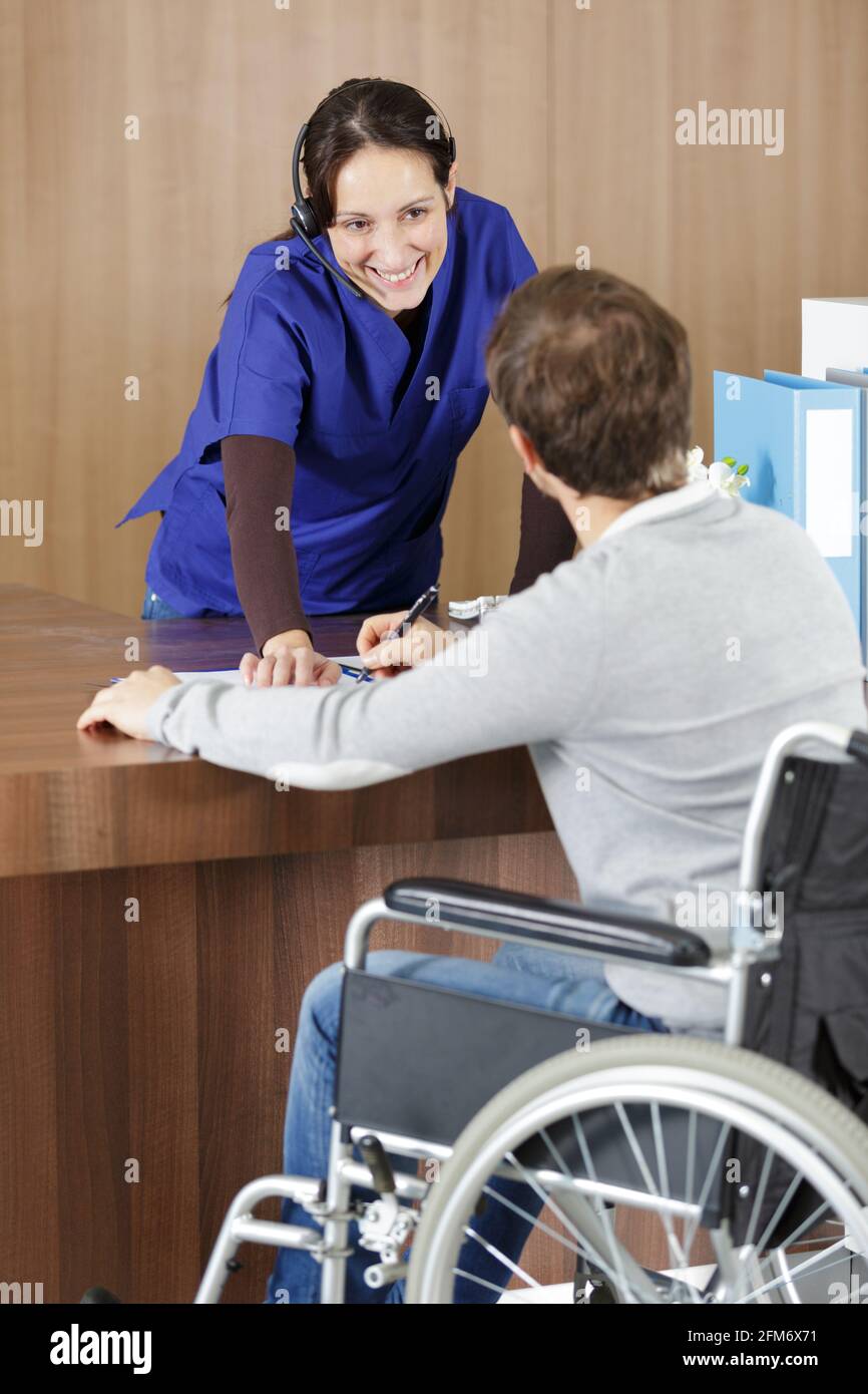 young man in wheelchair at hospital reception desk Stock Photo - Alamy