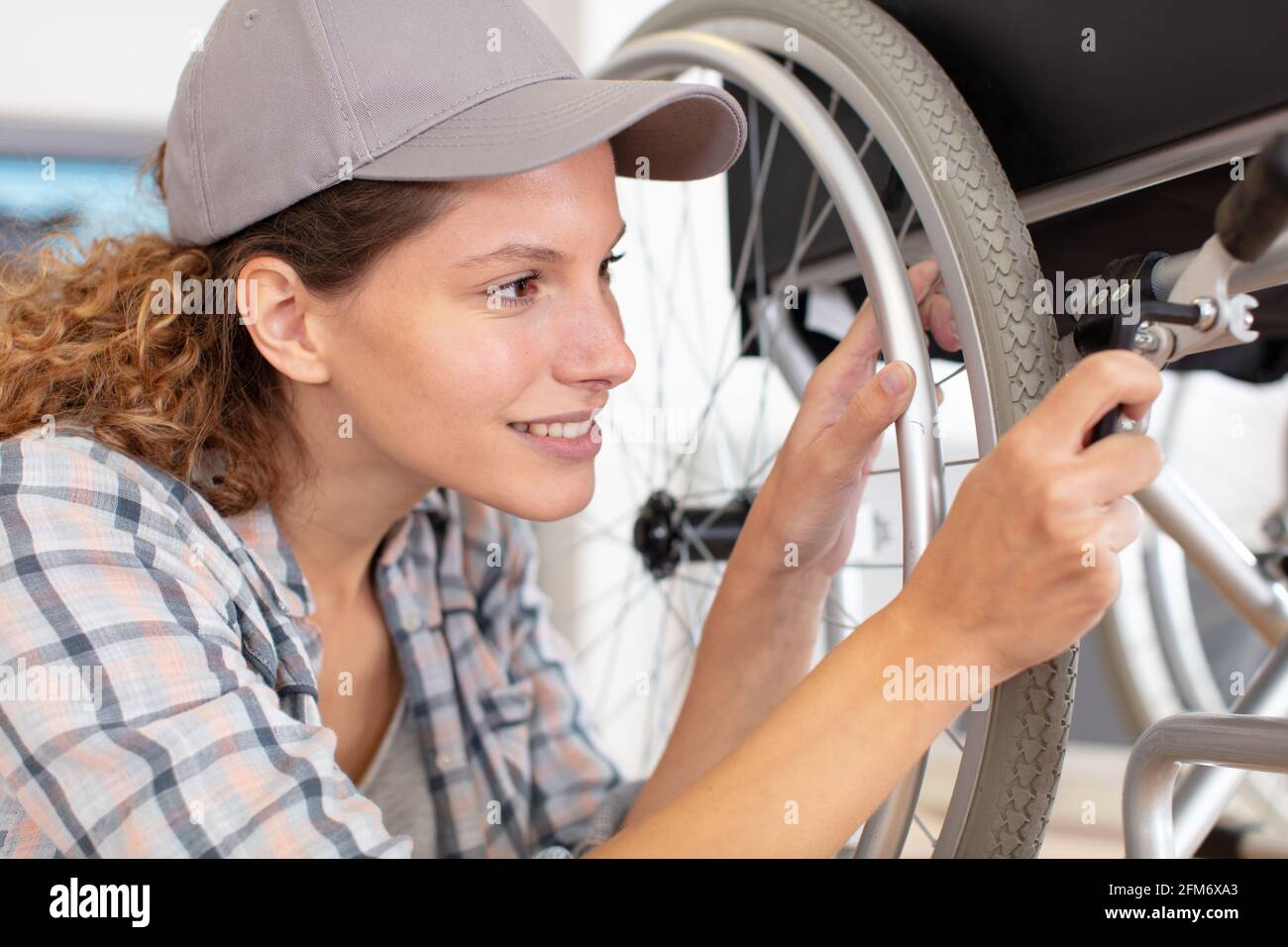 cheerful young female mechanic maintaining a wheelchair Stock Photo - Alamy