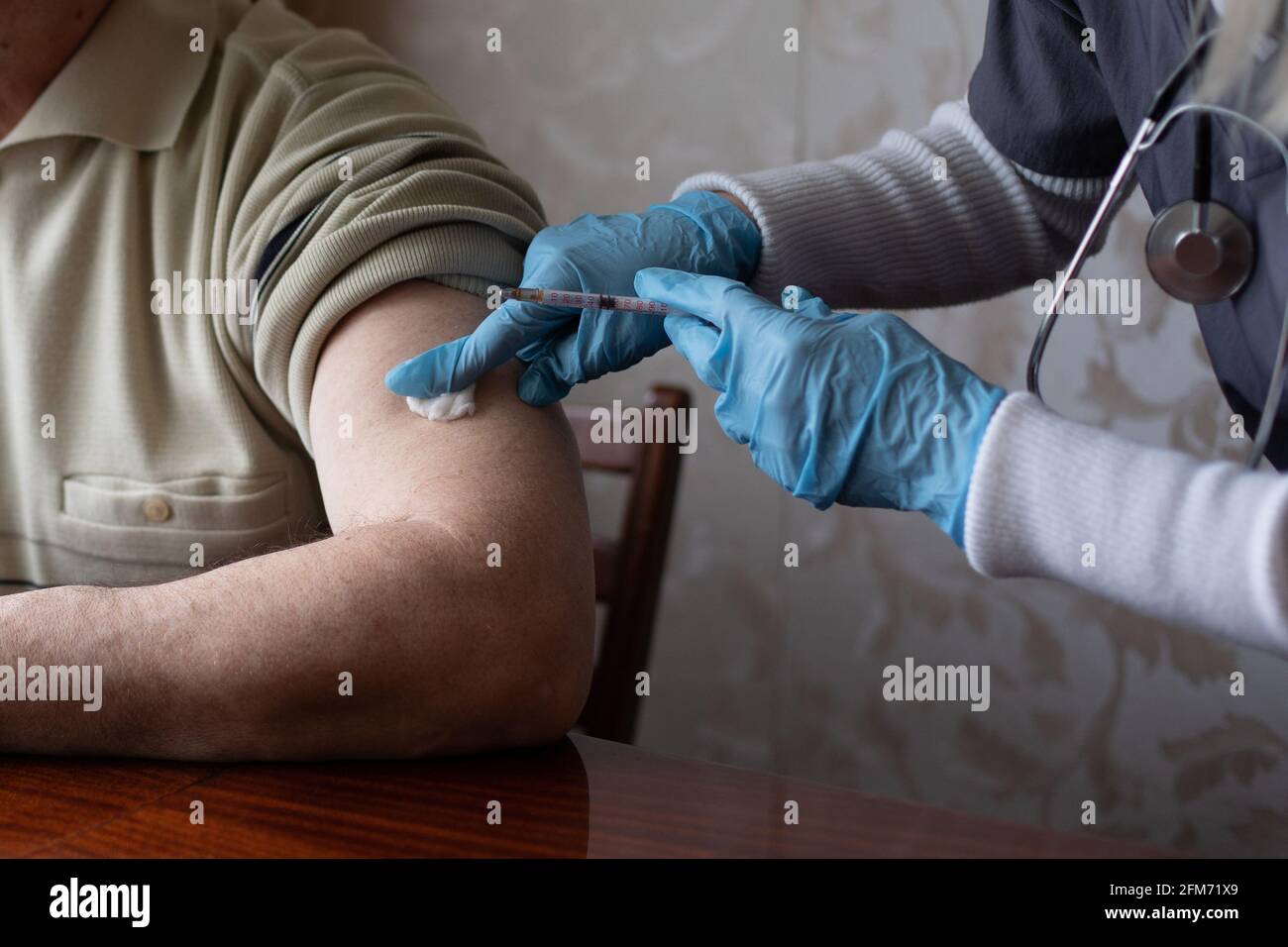 Doctor preparing vaccination shot to elderly patient by holding syringe ...