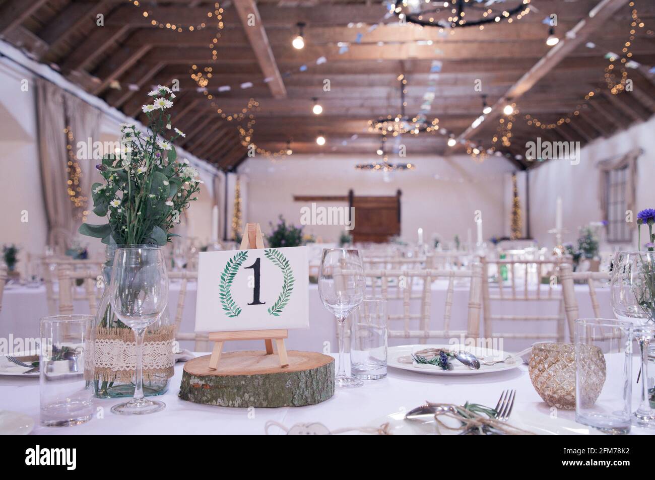Table number one at a barn wedding with rustic beams and rows of tables ...