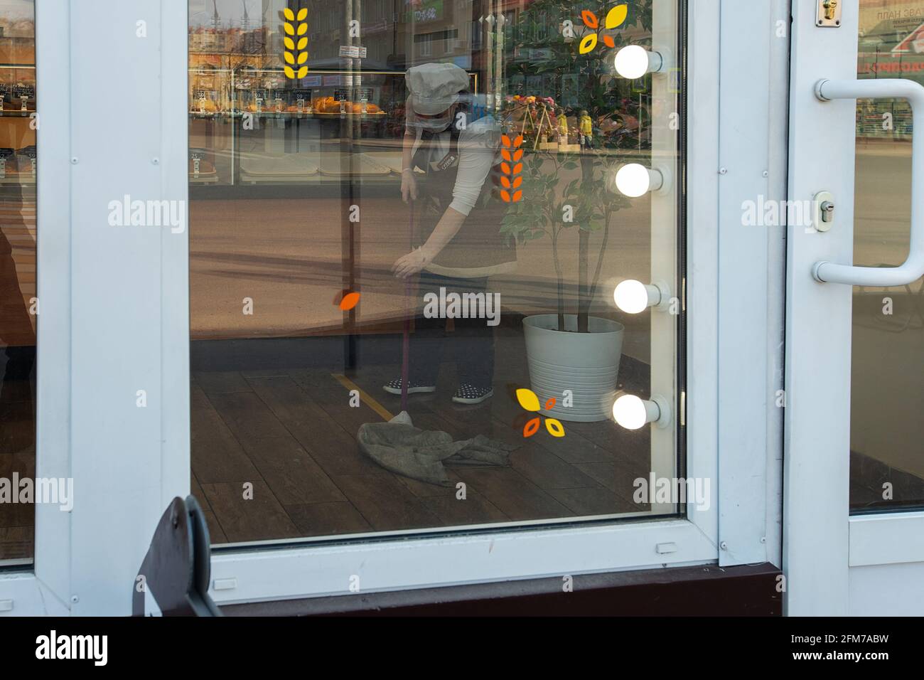 in the reflection of a glass window, a bakery clerk is mopping the ...