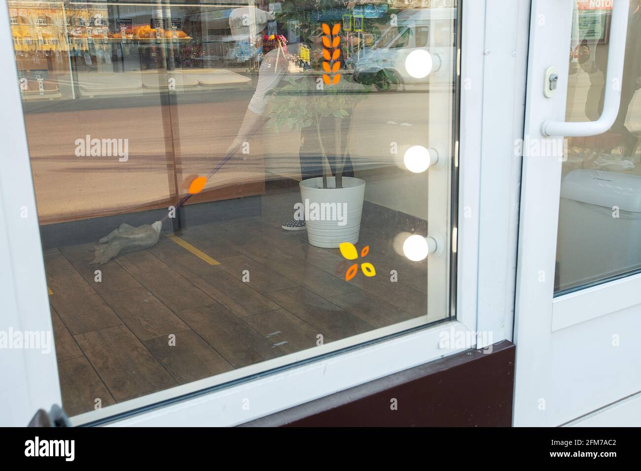 in the reflection of a glass window, a bakery clerk is mopping the ...