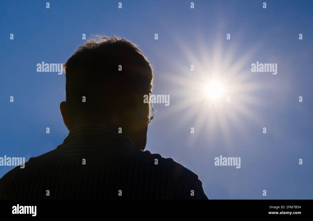 Silhouette of a man looking at the sun in the blue sky Stock Photo - Alamy