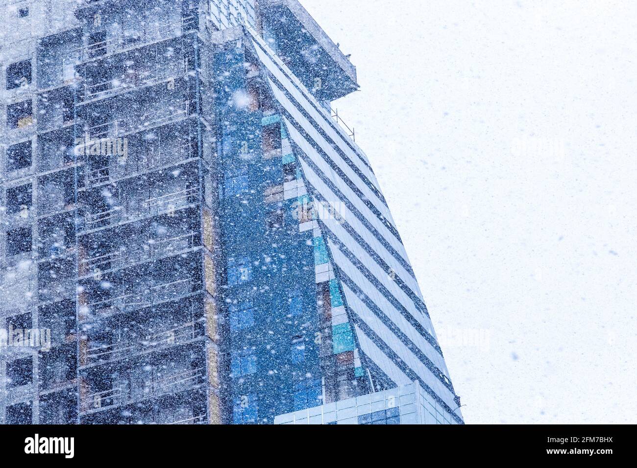 Unfinished new concrete modern city building in winter in cold and snow ...