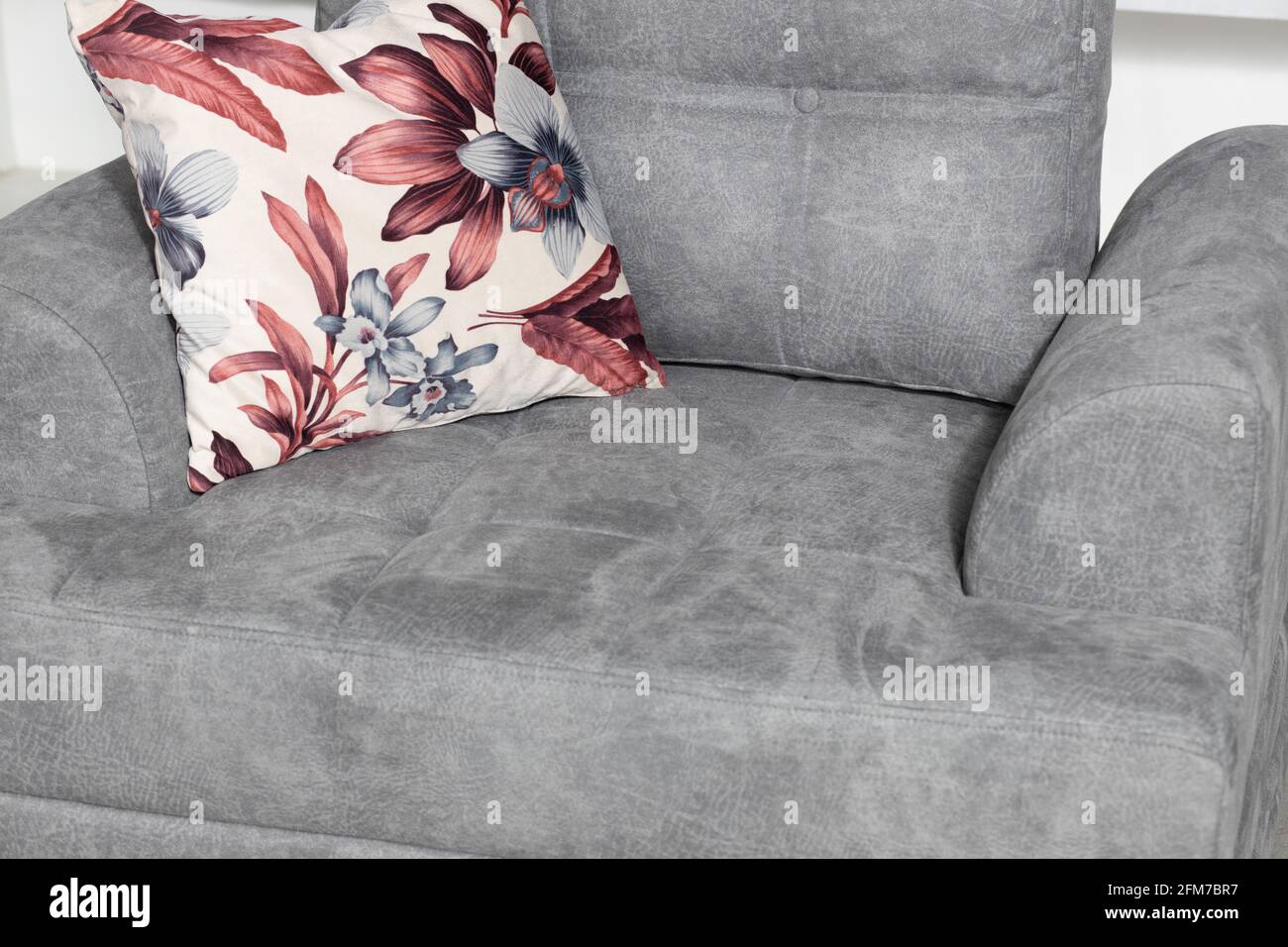 Closeup shot of a pillow with floral patterns on a grey armchair Stock Photo - Alamy