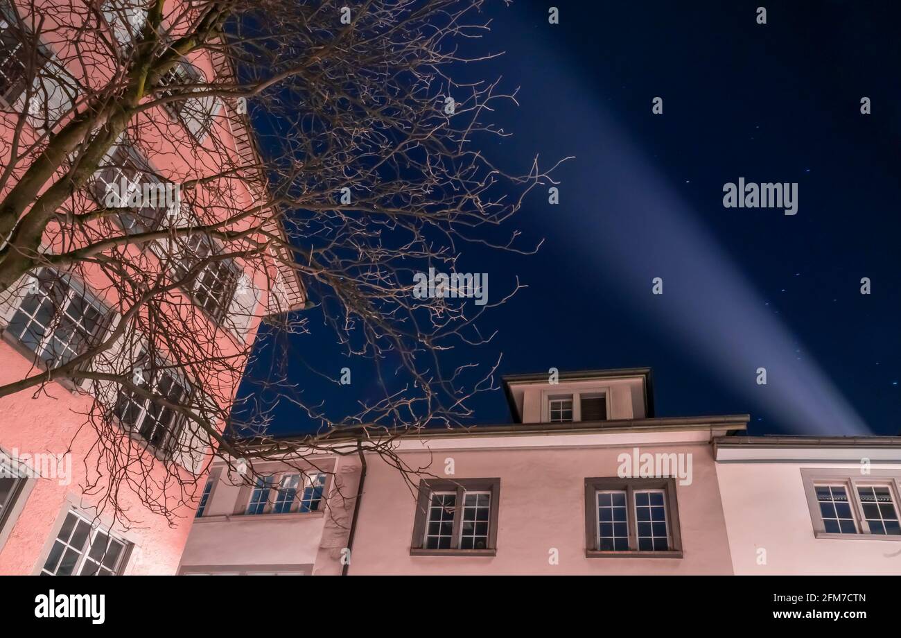 A beam of light from the attic window into the night sky above the ...